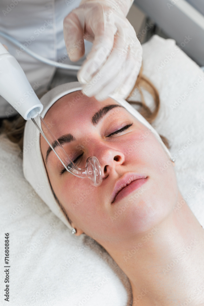 Young woman receiving face lift treatment with high-frequency wand ...
