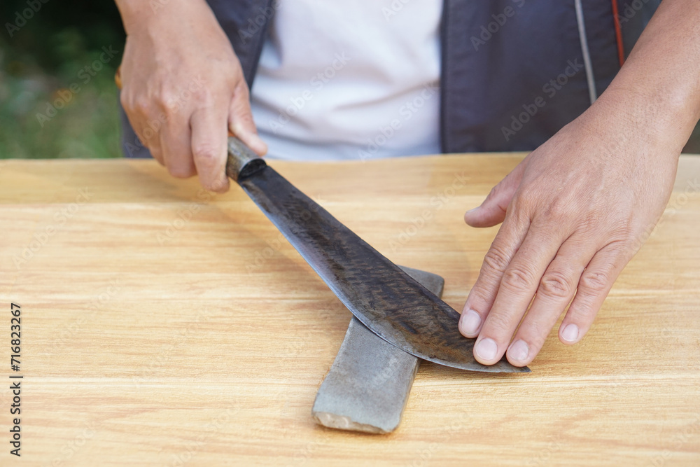 Closeup man hands sharpen knife on whetstone sharpener or grindstone ...