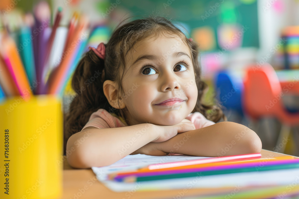 Excited little girl learns to draw with a colour pencil in an art class ...