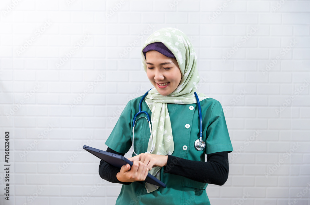 Female Muslim Islamic doctor surgeon using smart tablet device ...