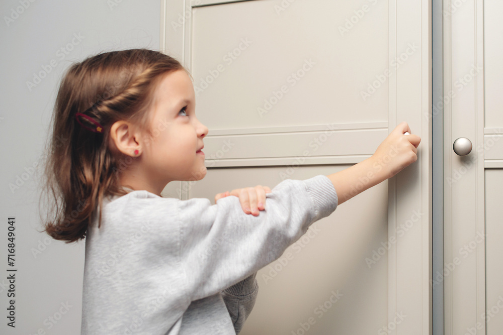 Little girl opens the cupboard. Cute baby girl playing with a wooden ...