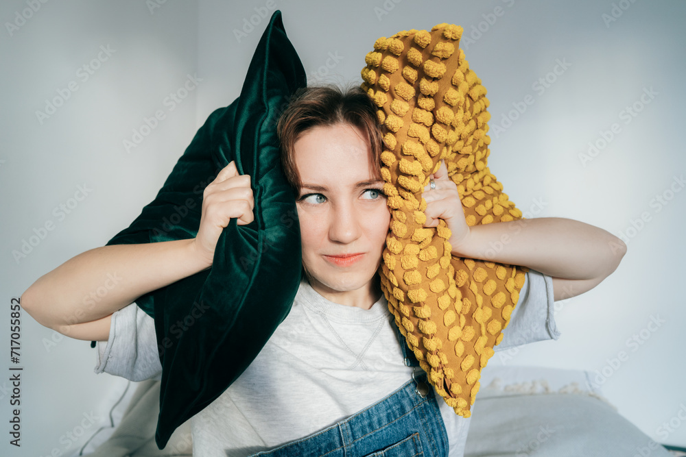 Irritated woman suffering from loud noise at home covering ears with ...