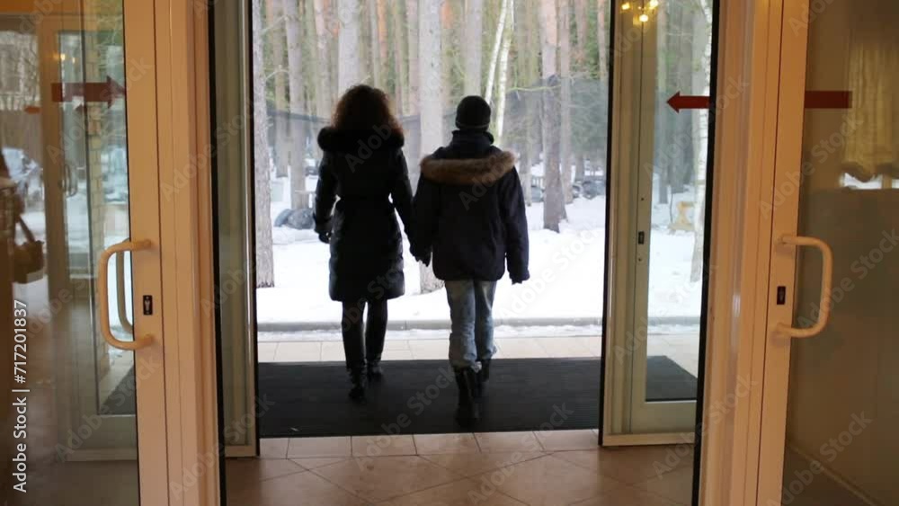 Back of woman and her son coming out of door at winter evening Stock ...