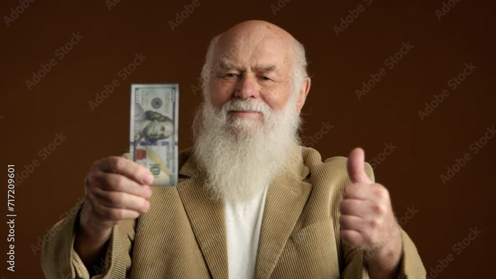 A cheerful senior gentleman with a full white beard proudly presents a ...
