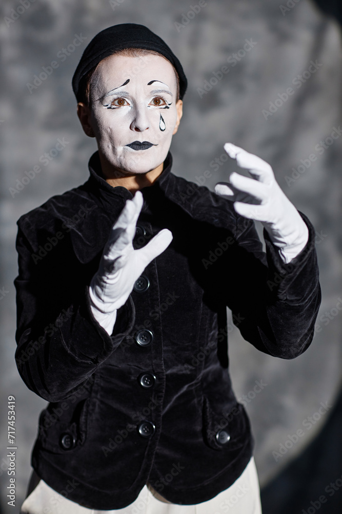 Dramatic vertical portrait of female mime artist performing on stage in ...