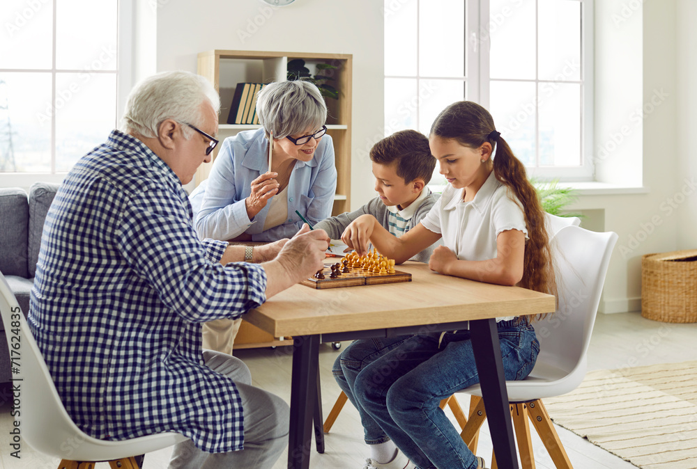 Retired grandparents together with grandchildren playing chess at a ...
