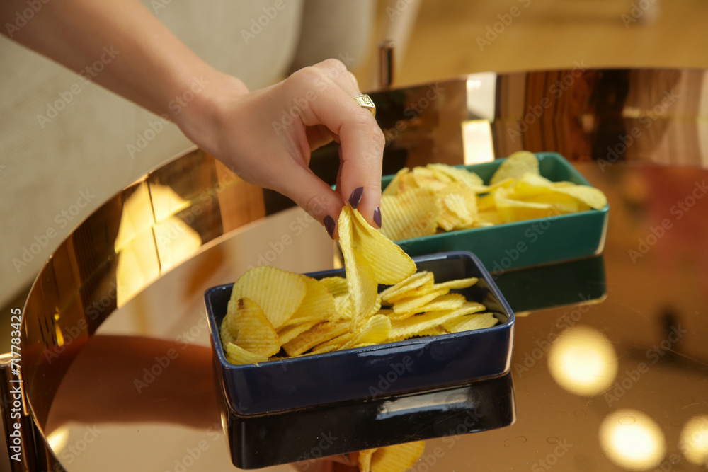 Young sad woman having unhealthy snack, eating potato chips in the ...
