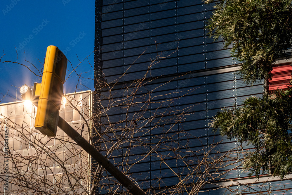 Yellow traffic light at an intersection in the middle of a cityscape in ...