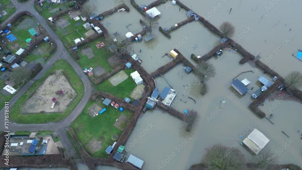 Tilting aerial view of flooded camping site with houses and gardens ...