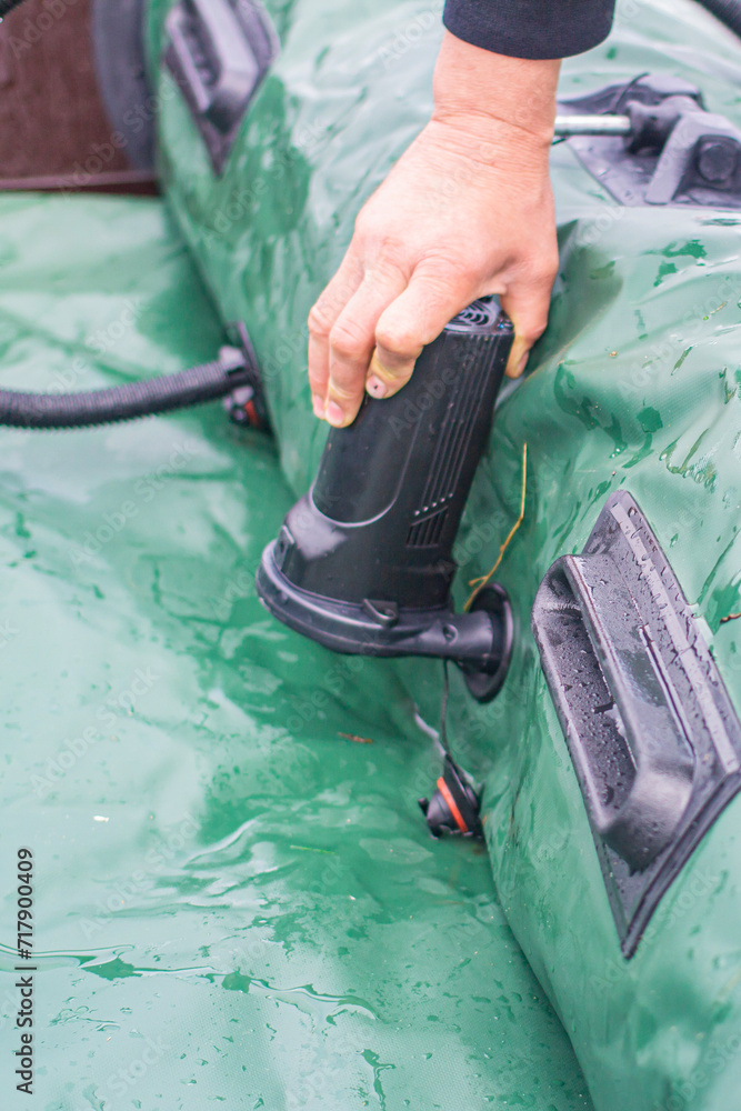 man inflating a rubber boat with a hand electric pump close-up, front ...