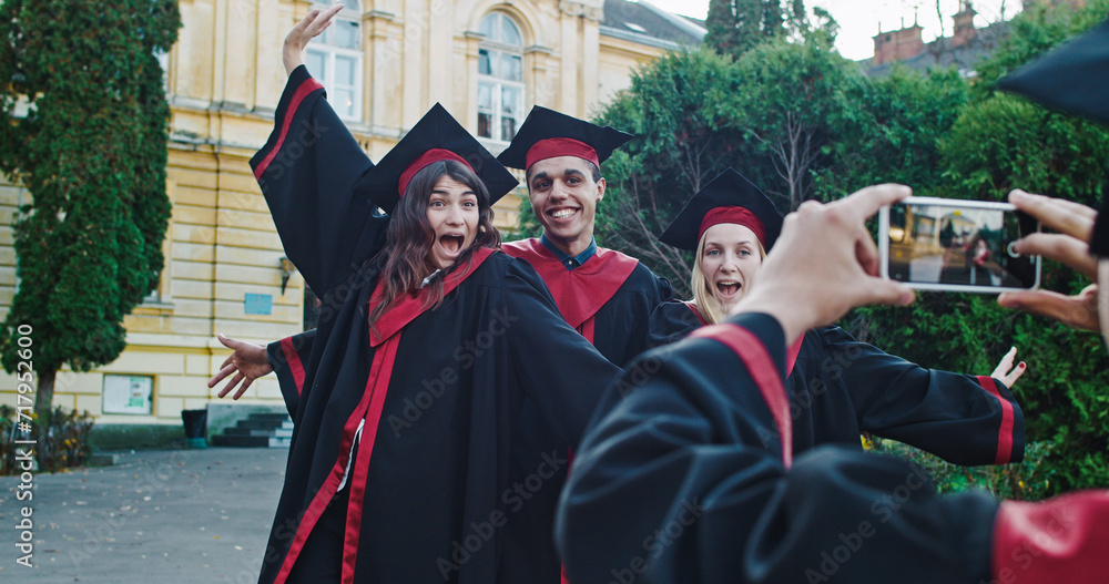 Rear of the guy in academic cap taking photos on his smartphone camera ...