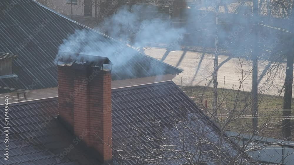 Smoke comes out of the chimney of a modern house. Pipe on the roof. A ...