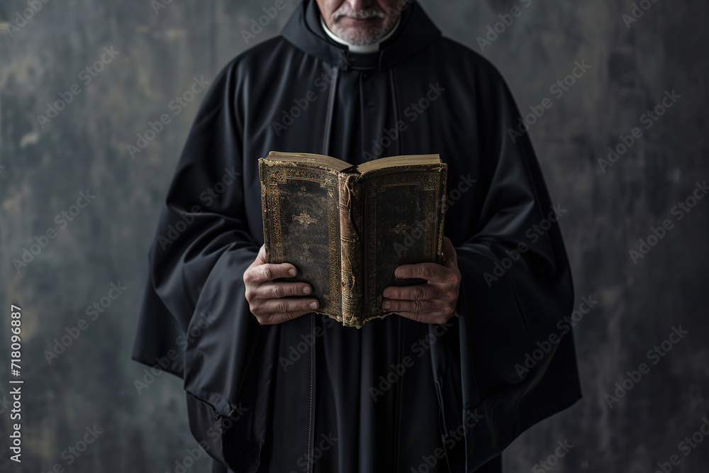 a catholic christian church priest wearing black cassock robe holding ...