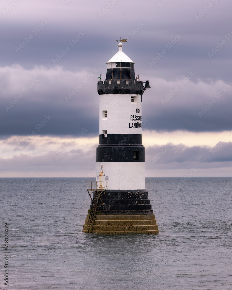 Black and white stone lighthouse in the water at high tide with ...