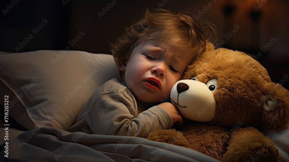emotional moment of a one-year-old child crying in bed with a teddy ...