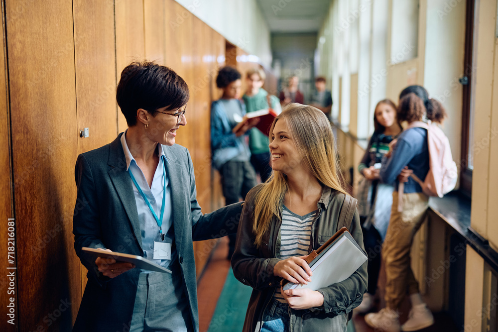 Happy teenage girl talking to her teacher in high school hallway. Stock ...