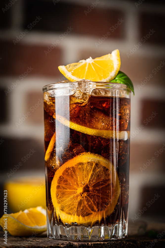 Cuba Libre in a glass with brown rum, cola, mint and lemon on brick ...