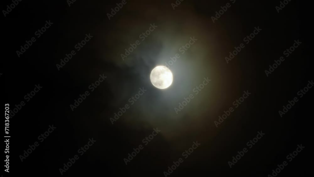Full moon in the dark night sky with fast flying clouds. The lunar ...