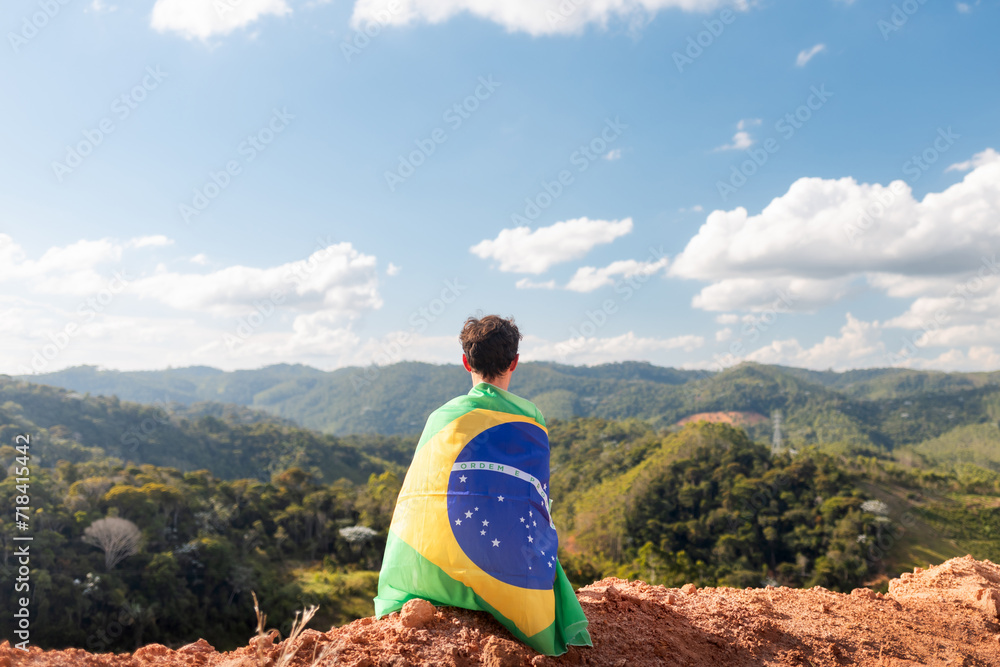 Man sitting atop a mountain with the Brazilian flag wrapped around him ...
