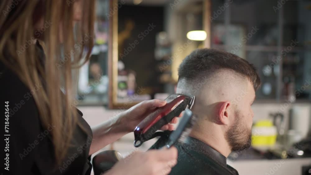 Young female barber making men's undercut haircut hairstyle using ...