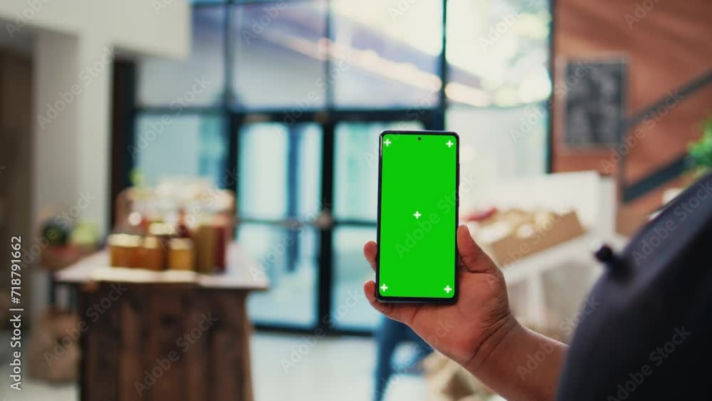 Retailer holding mobile phone with greenscreen layout, working at ...