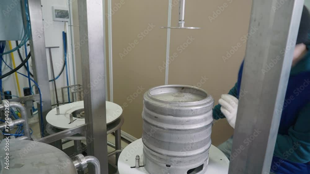 Worker places a beer barrel onto the machine for washing. Automated ...