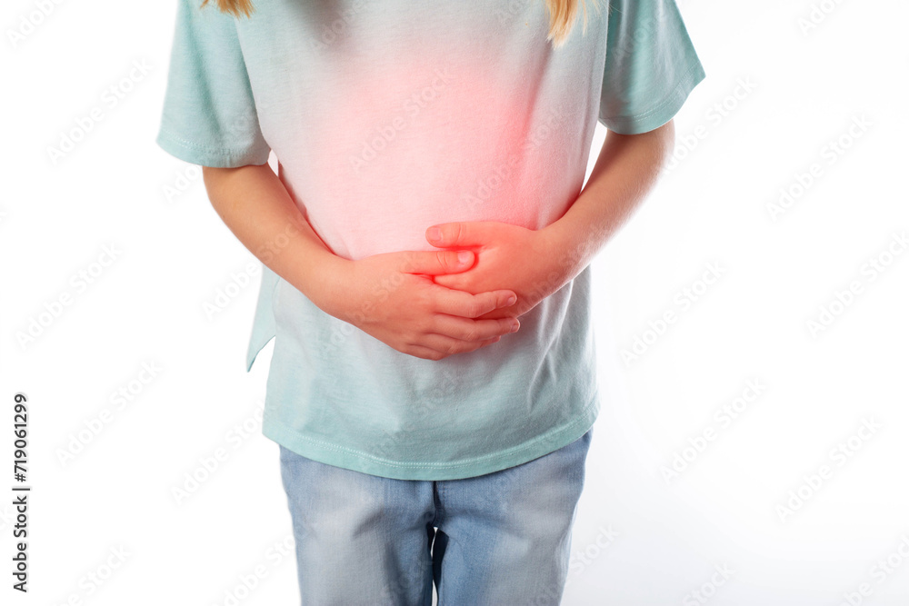 A seven-year-old girl in a green T-shirt holds her inflamed red stomach ...
