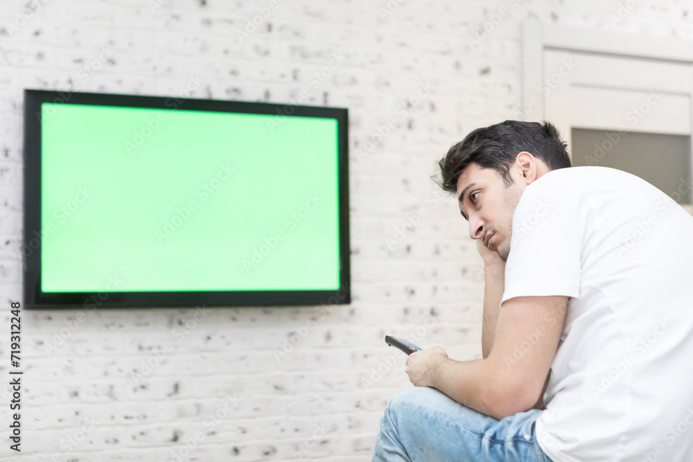 Frustrated man on the couch watching tv. Bad news and Green screen ...