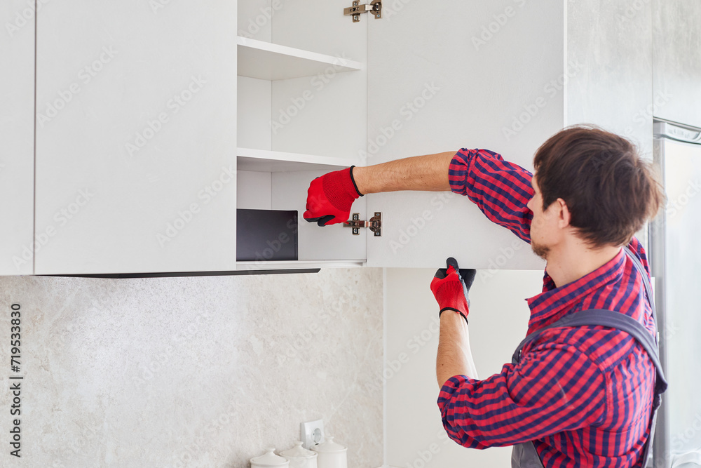 Professional furniture worker assembling kitchen closets and cabinets ...