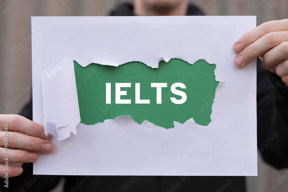 Man holding white and green sheets of paper with text: IELTS. Concept ...