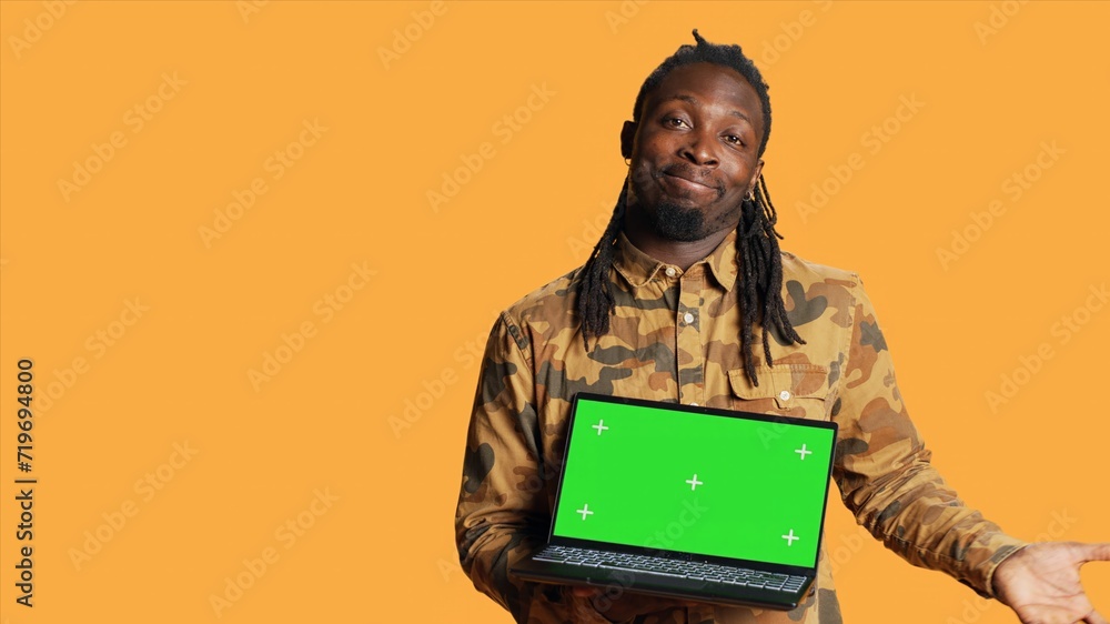 Young guy showing pc with greenscreen layout on camera, pointing at ...