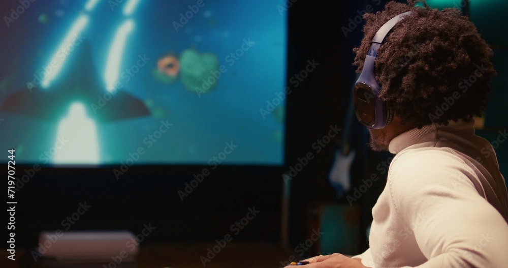 Gamer playing science fiction flying game on ultrawide smart TV ...