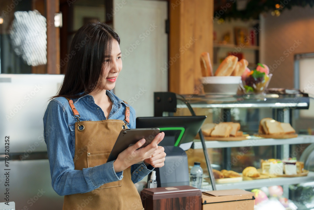 Beautiful Asian barista holds a tablet showing customers a menu and ...