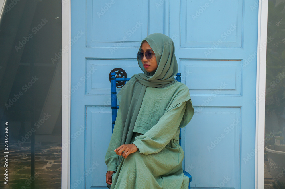 Beautiful Muslim woman in hijab sitting on a chair wearing a green ...