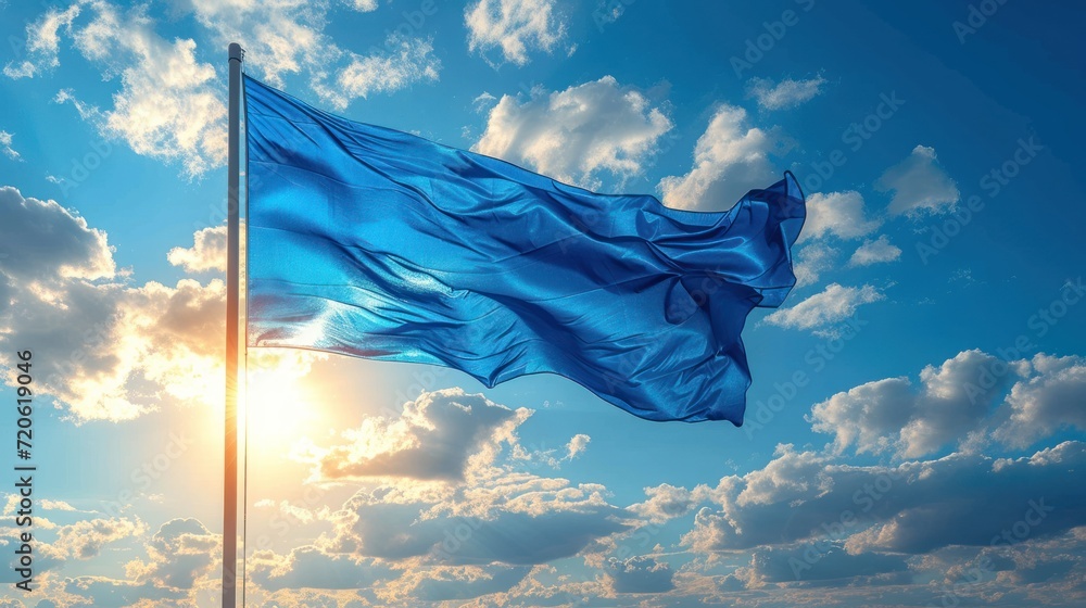 a blue flag blowing in the wind under a cloudy blue sky with the sun ...