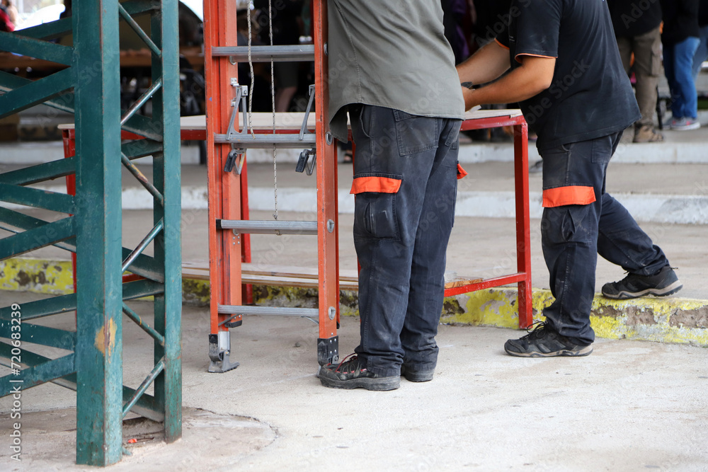 Workers working with work clothes and metal ladder. Workers assembling ...