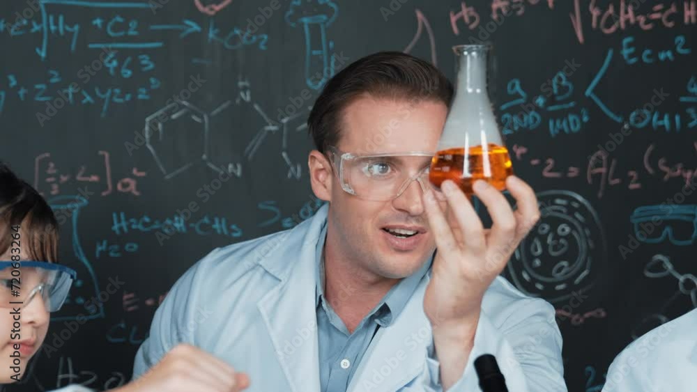Smart teacher holding solution in beaker while student doing experiment ...