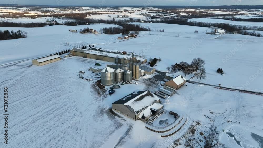 Wide aerial view of Midwest grain farm and bins covered in winter snow ...