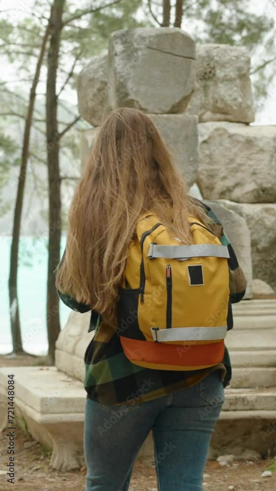 Vidéo Stock Vertical video. A female tourist with a backpack walks ...