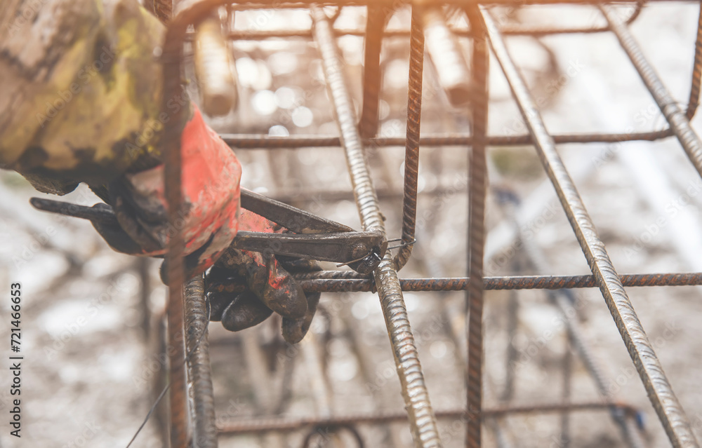 A worker uses steel tying wire to fasten steel rods to reinforcement ...