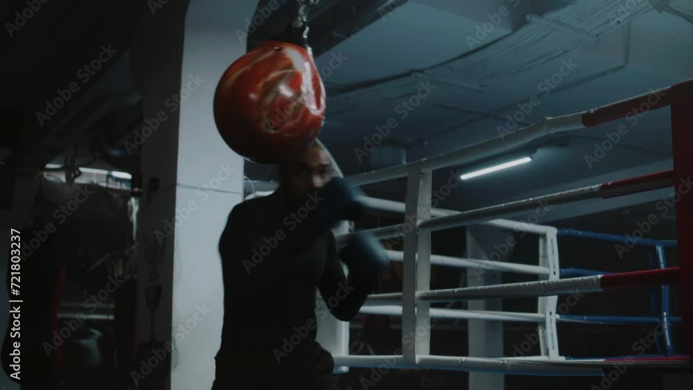 Fit African American fighter hits punching bag while training in dark ...