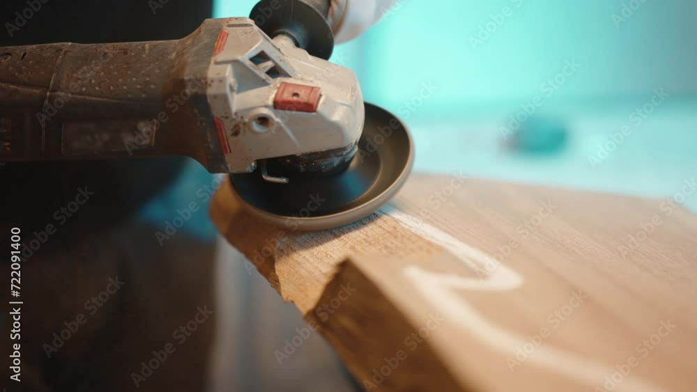 Carpenter in protective uniform using angle grinder for sharpening wood ...