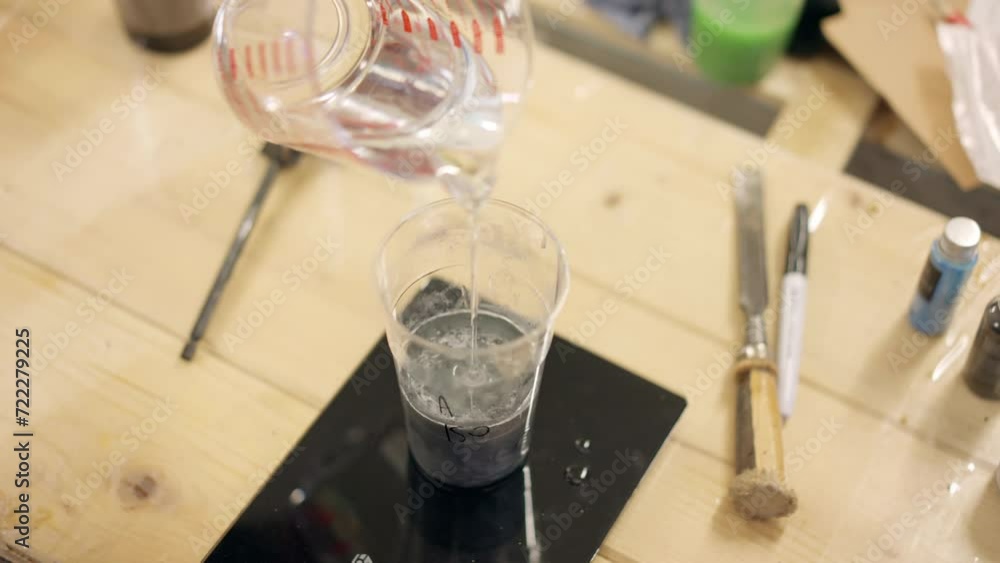 Process of pouring transparent epoxy resin into plastic cup on scales ...