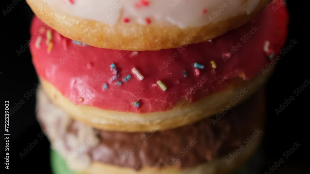 A tall tower of multi-colored donuts with different flavors lying on ...