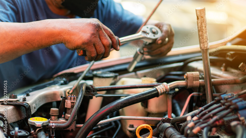 Mechanic using wrench while working on car engine at garage workshop ...