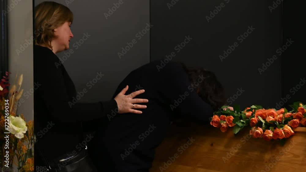 funeral ceremony. a widow and family members are crying near the coffin ...