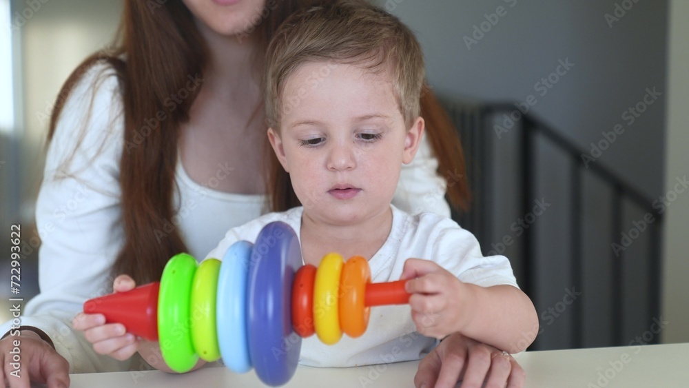 the child collects a toy pyramid. mom plays with son at home happy ...