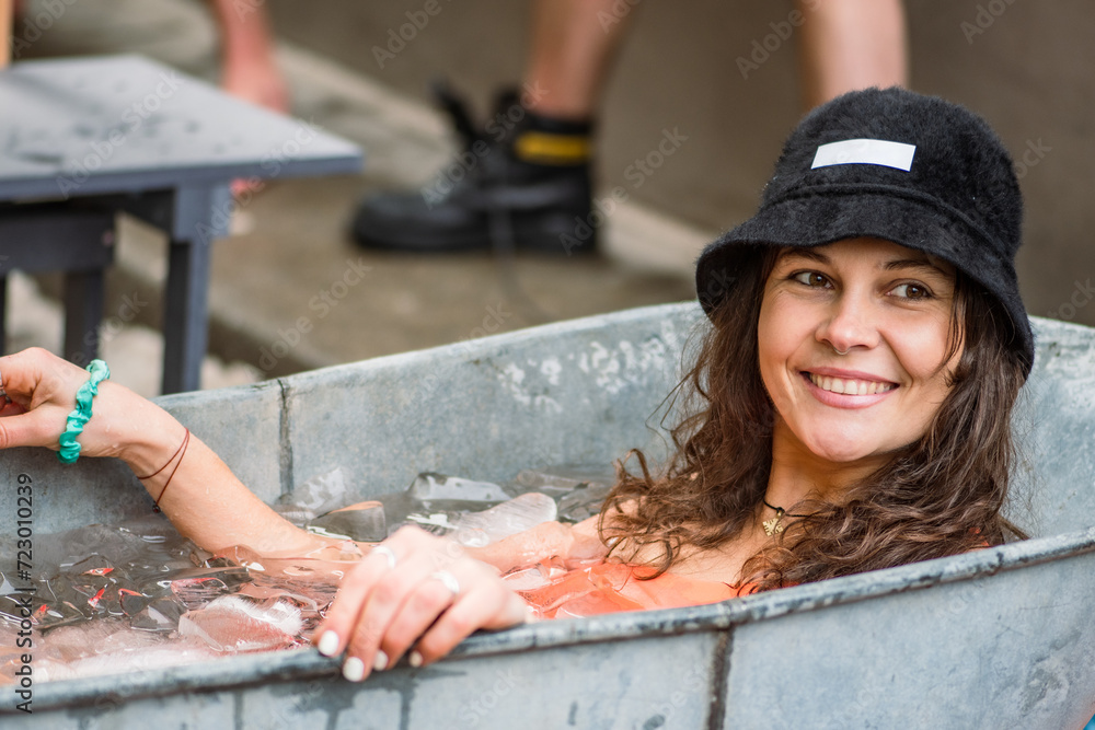 Pretty girl or woman wearing a hat, smiling and ice bathing in the cold ...
