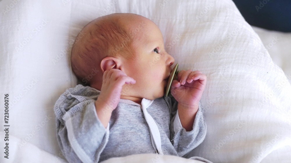 newborn with pacifier. baby close-up with a pacifier lies in bed at ...