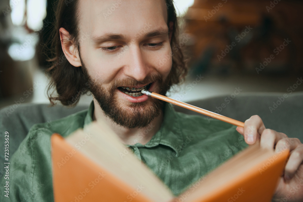 Excited young man, student sitting in public library and reading ...